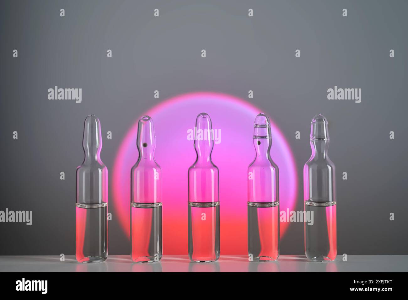 Several ampoules for injection with medicines on a pink background ...