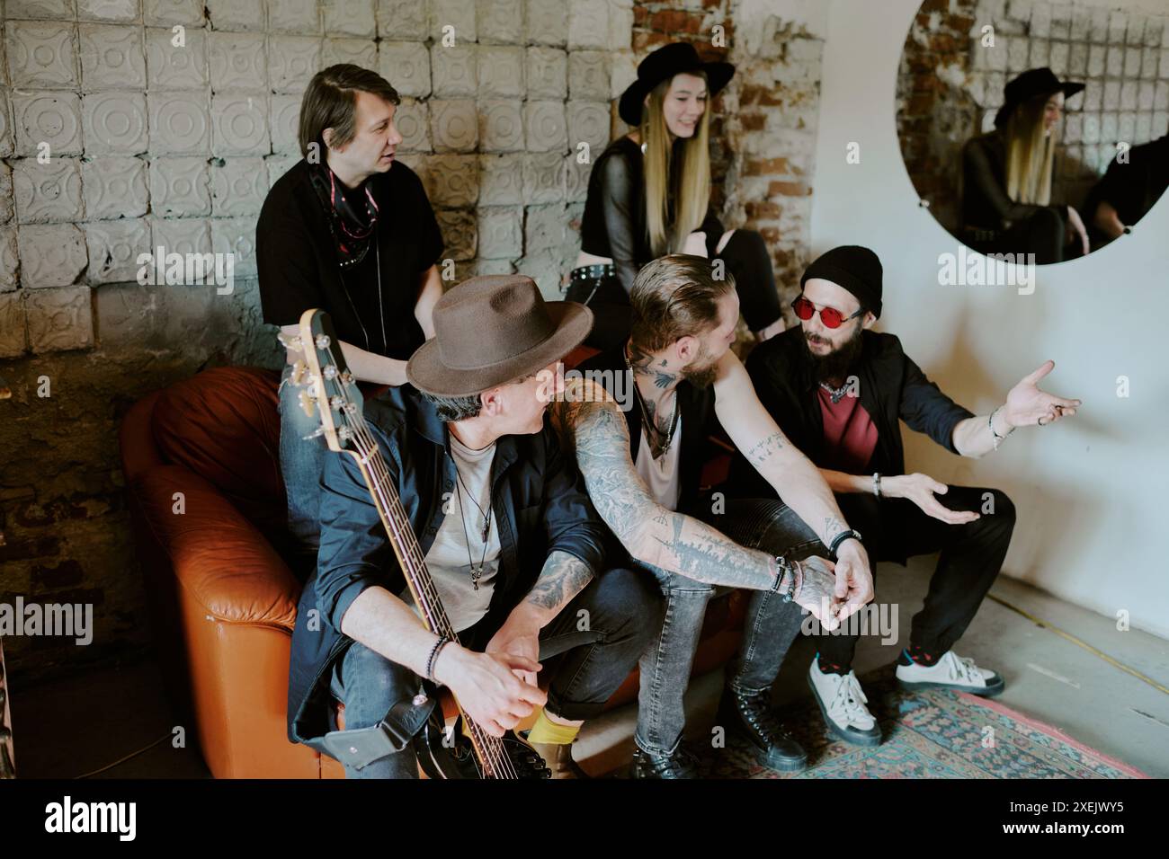 Group of male and female rock musicians sitting on leather couch having ...