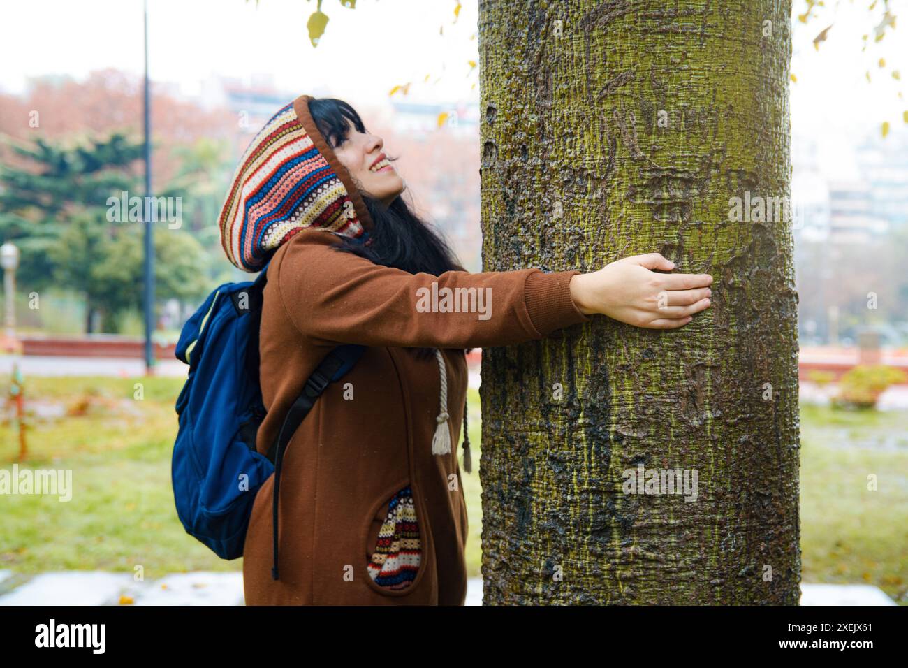 Young Nature-Loving Woman is hugging tree and is looking at it and ...