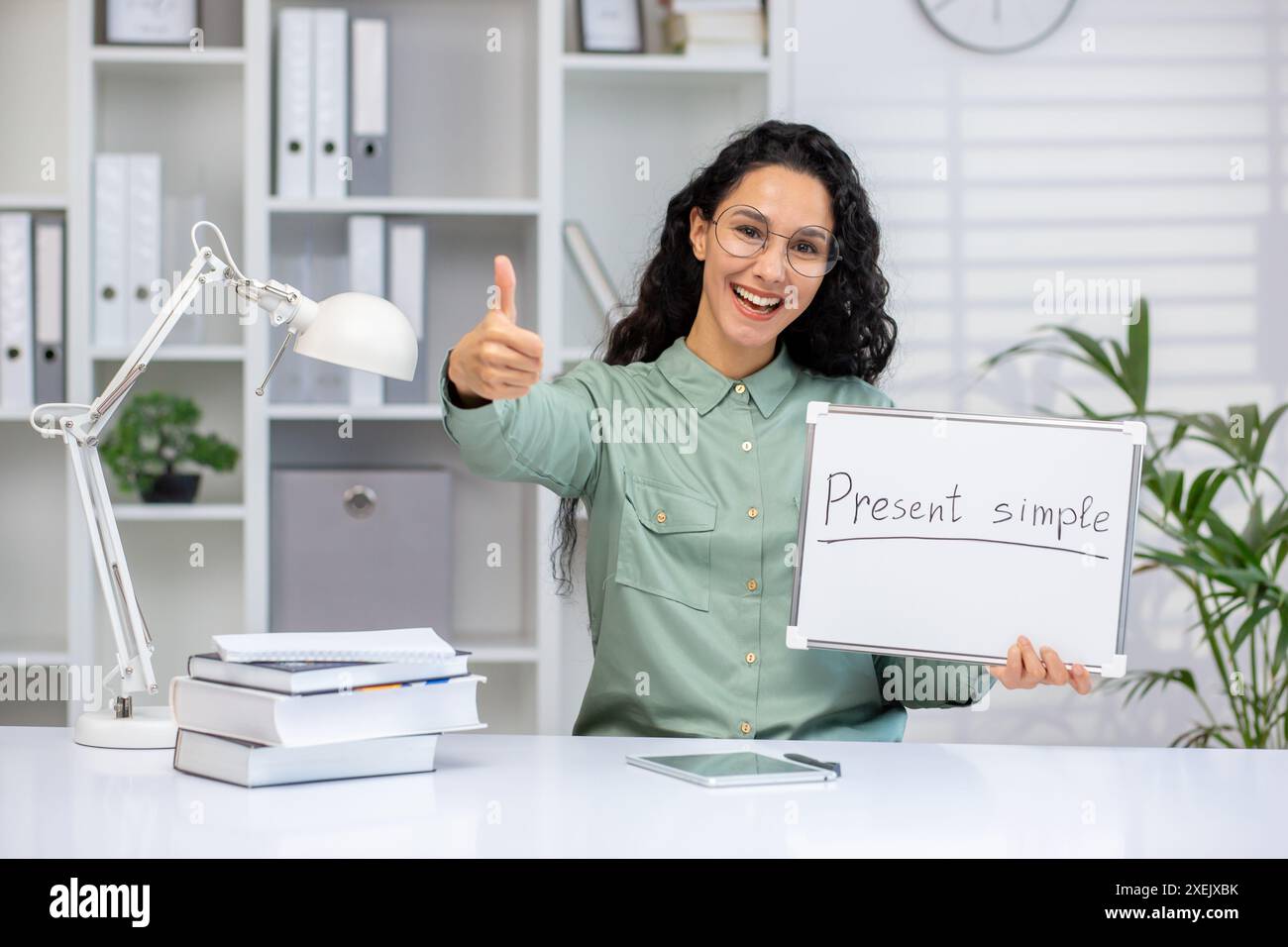 Enthusiastic teacher giving thumbs up during online English lesson ...