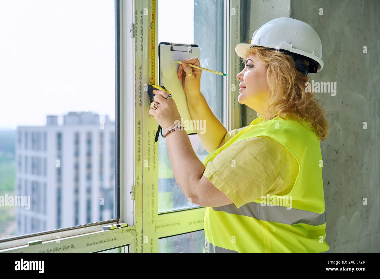 Female window decorator designer measuring window with tape measure ...