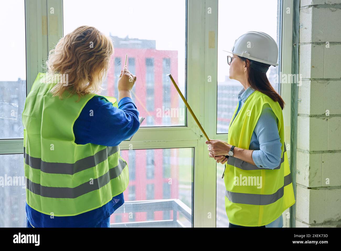 Two female industrial workers taking measurements of windows for ...