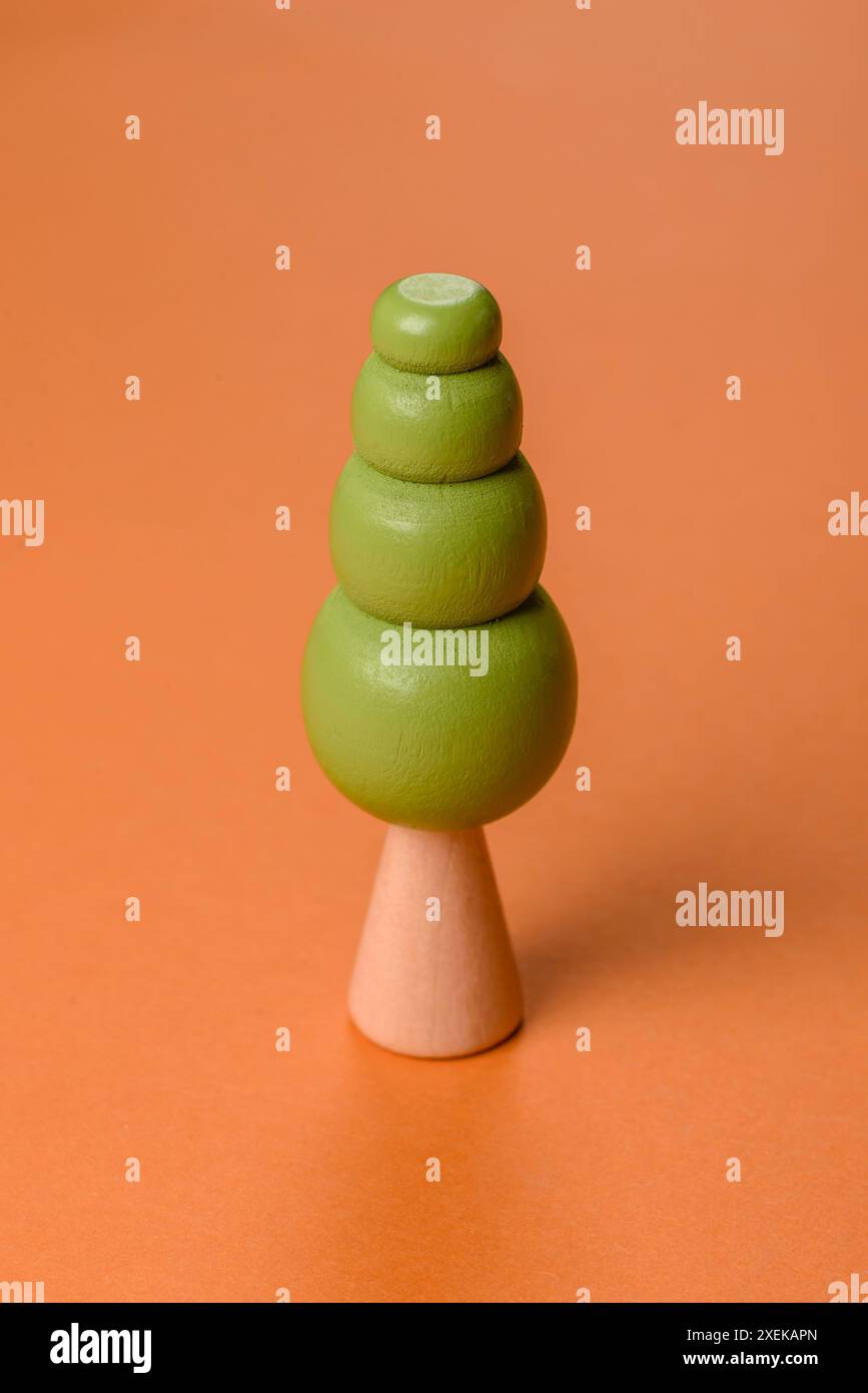 Wooden model of a tree with a green crown and trunk on a orange ...