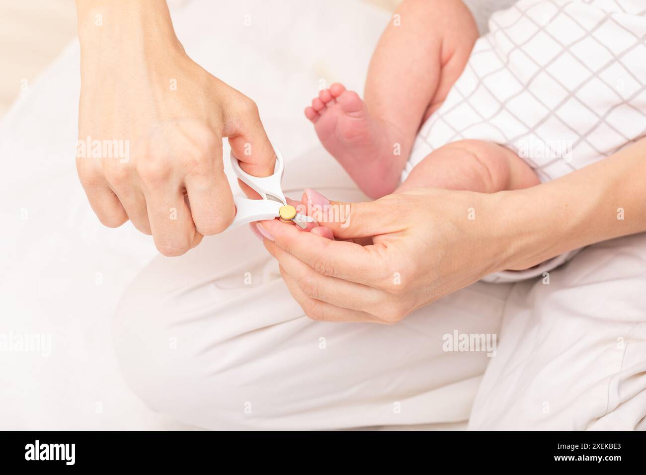 Mother uses special baby nail scissors to trim toenails of newborn baby ...