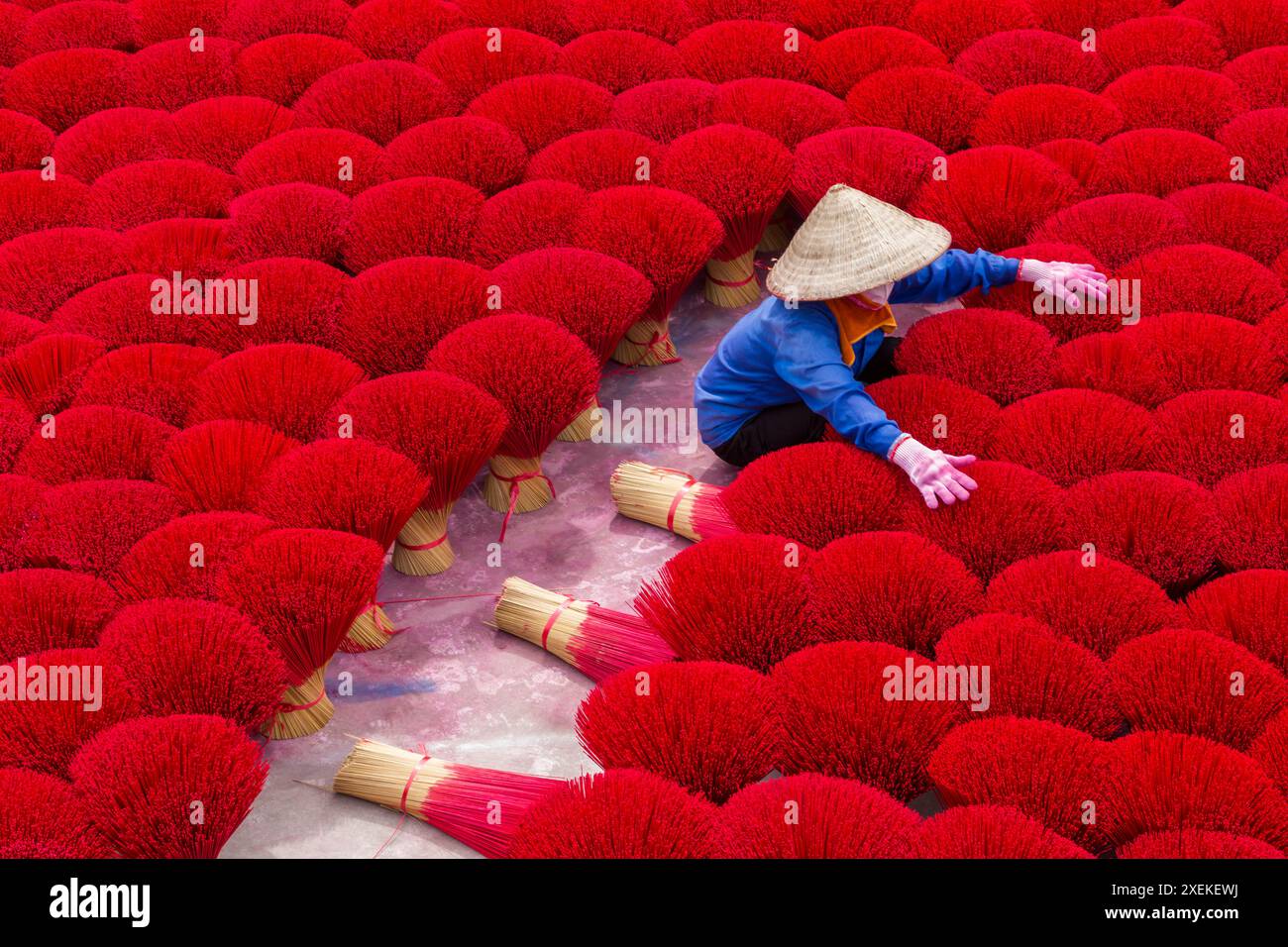 Vibrant red incense is laid out on the ground to dry in the sun at ...
