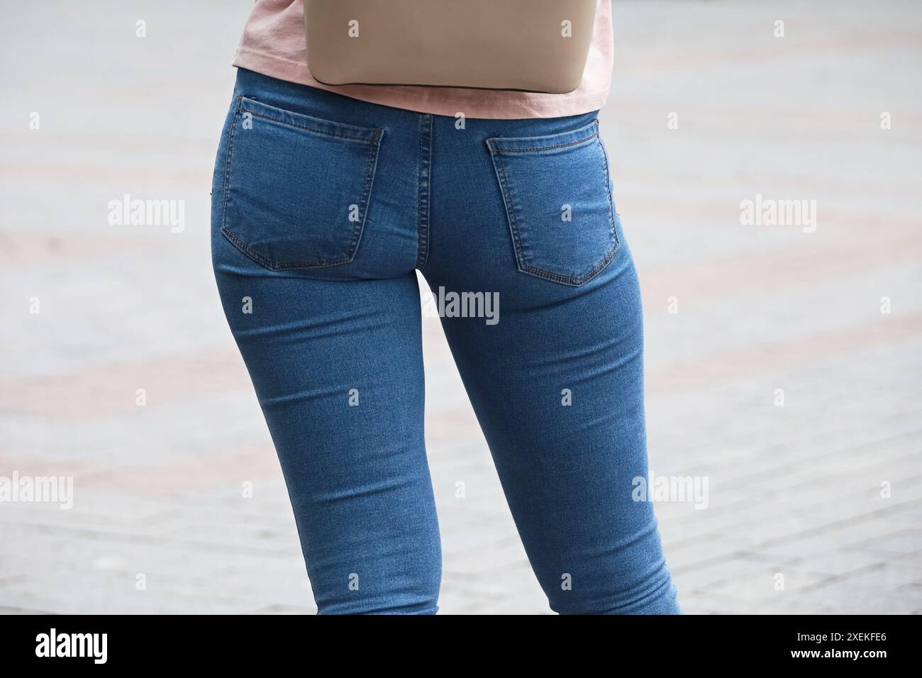 Woman in blue jeans standing on a street, back view. Female fashion in ...