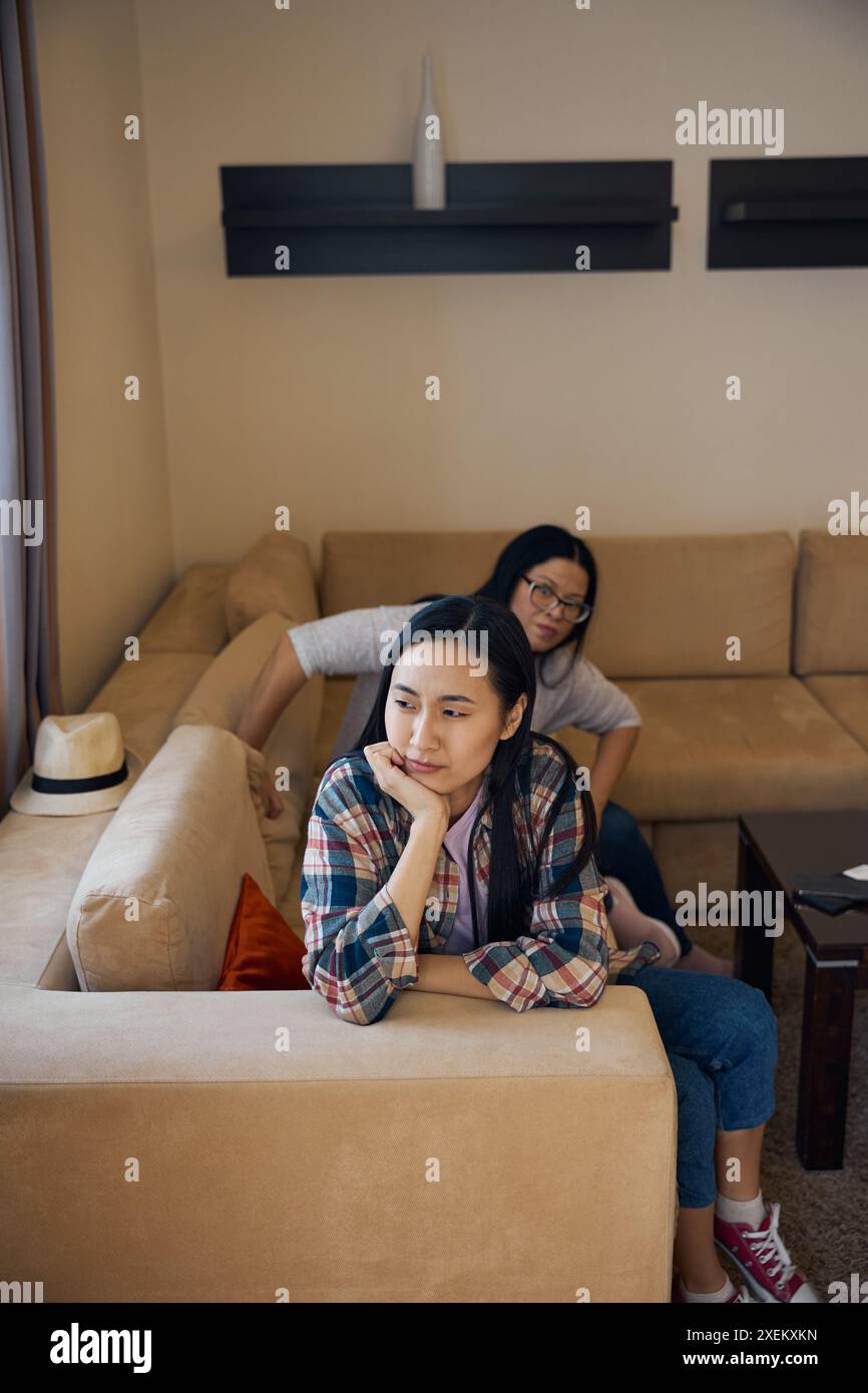 Upset daughter ignoring her irritated mother after home conflict Stock Photo - Alamy