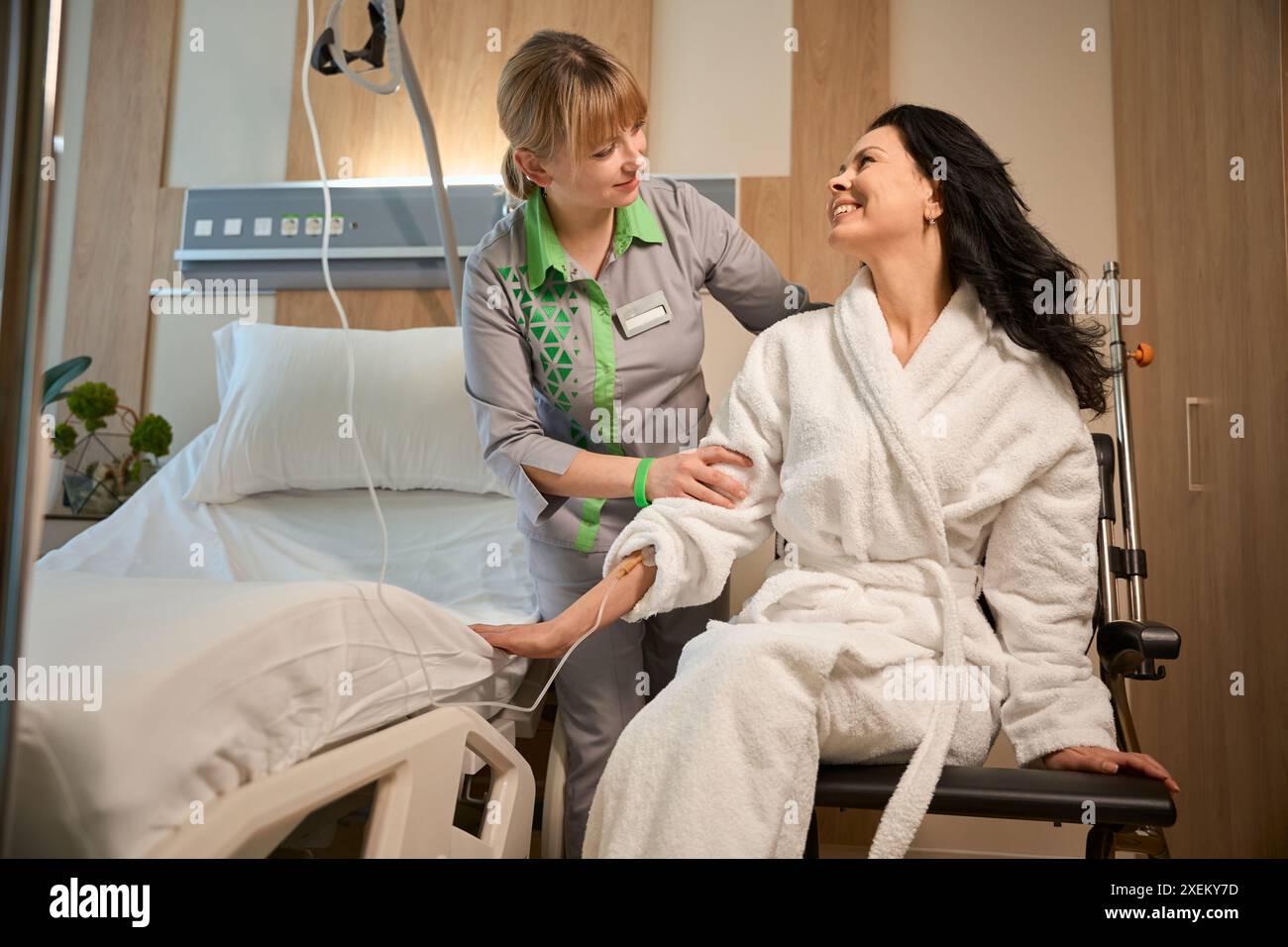 Health worker helps a patient transfer from bed to wheelchair Stock ...