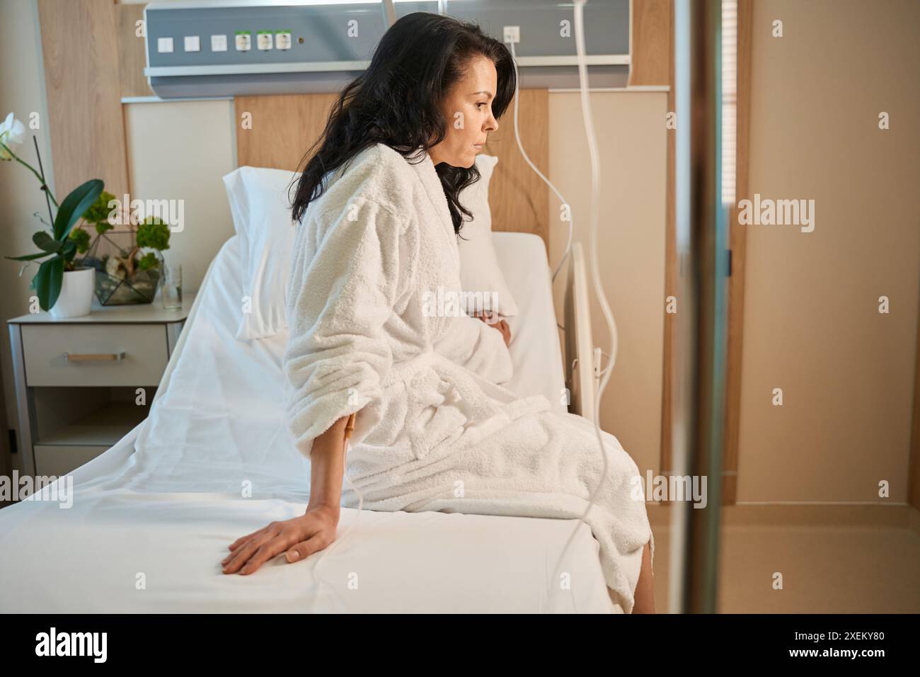 Sad female patient sitting in a modern hospital room Stock Photo - Alamy
