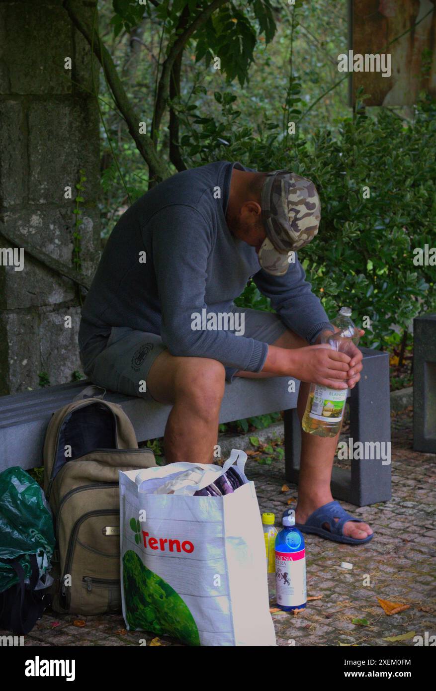 Homeless guy sitting on a bench in a park Stock Photo - Alamy