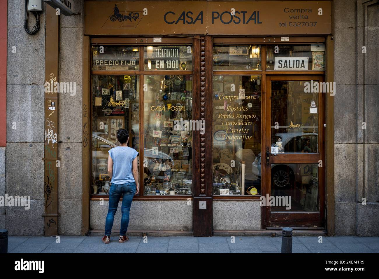 Woman window shopping at the window of an antiques shop in Chueca of ...