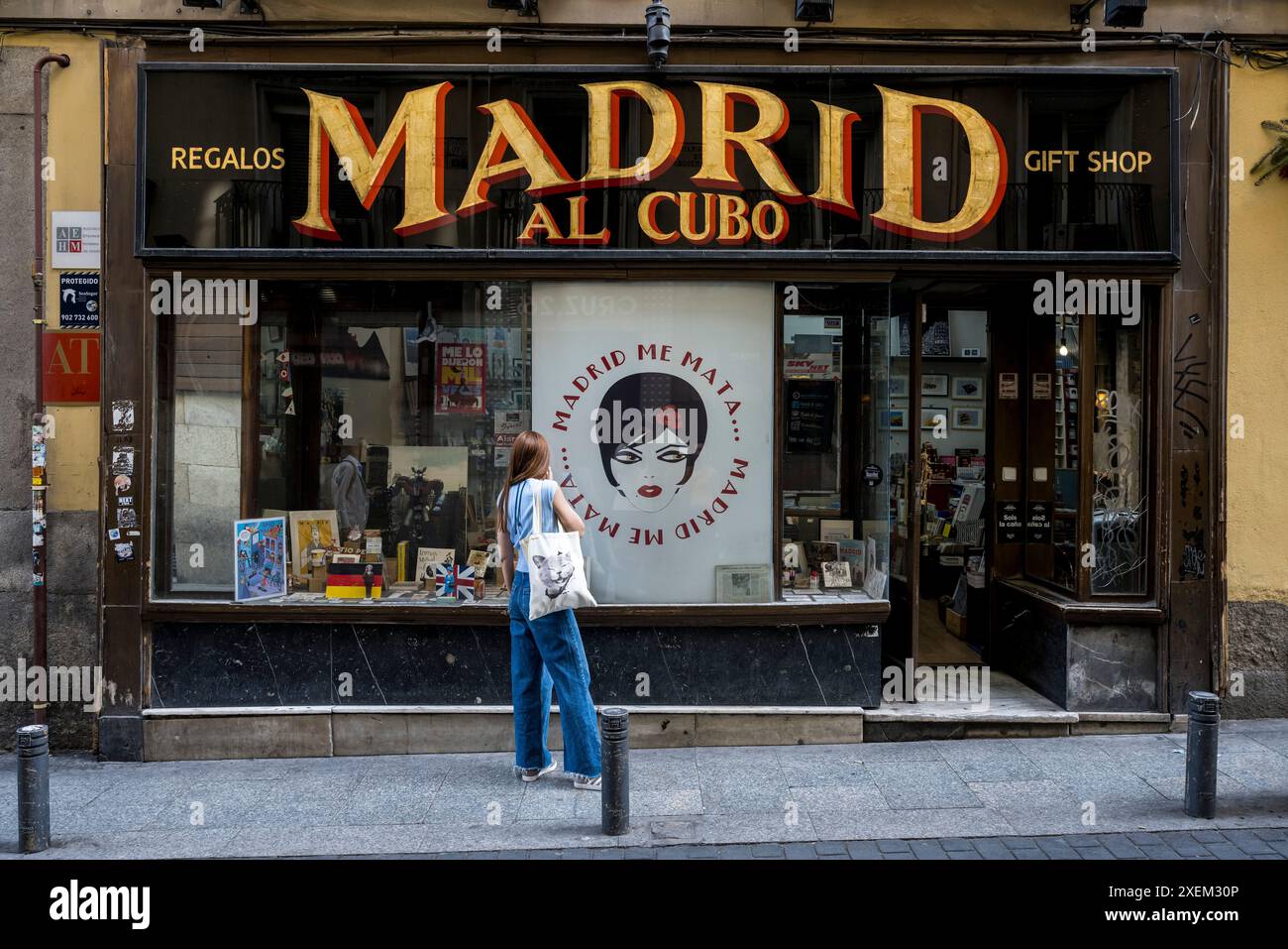 Young woman stands looking in the window of a gift shop in Madrid ...