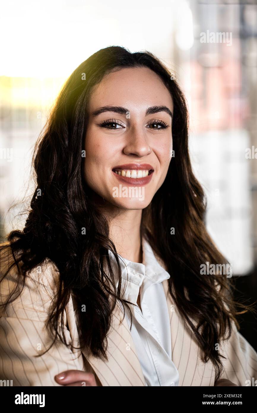 Confident young businesswoman smiling in modern office setting. She is ...