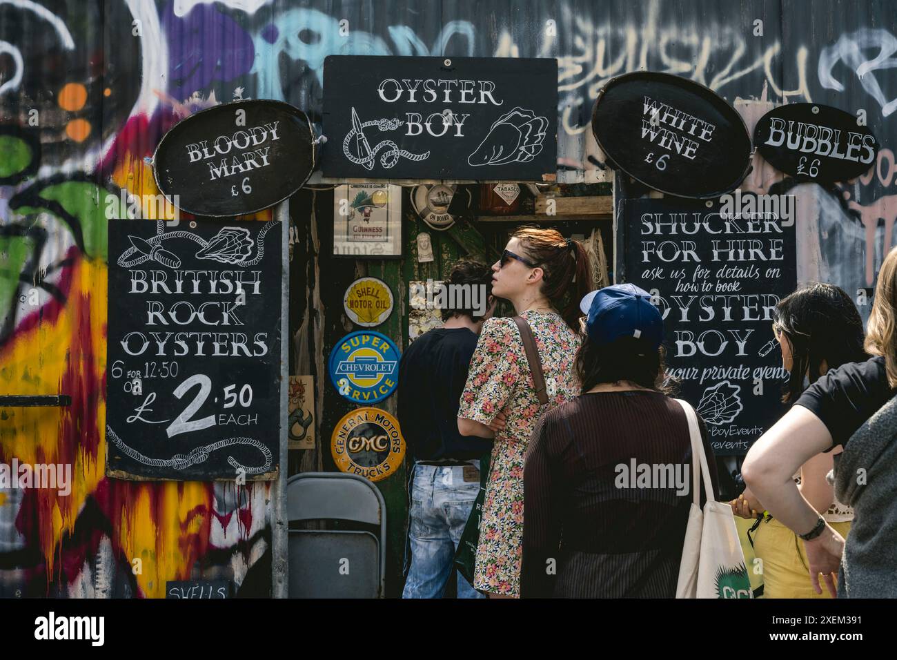 Customers line up outside an Oyster Bar in East London, UK, with menu ...