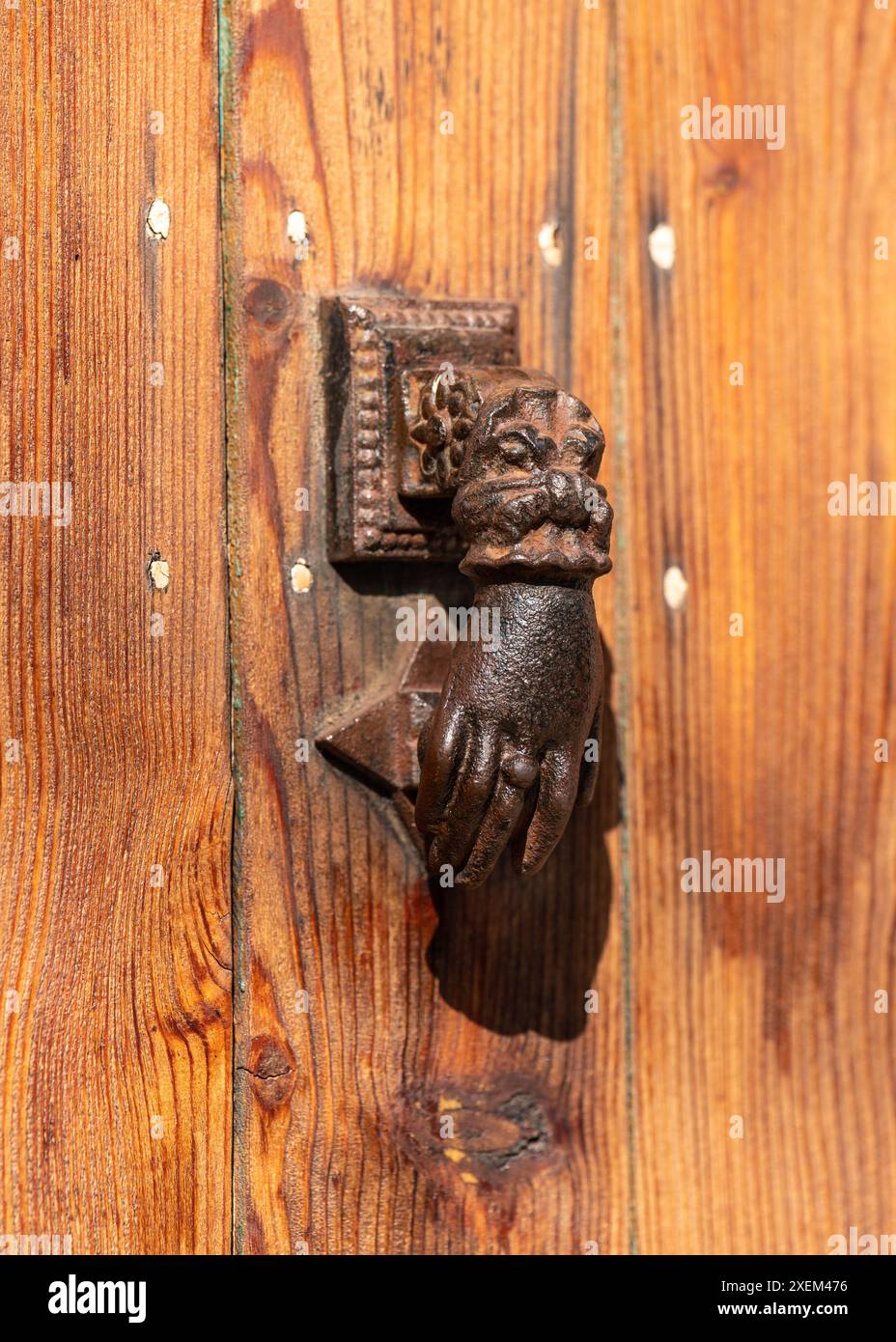 An old wooden door with an iron handle in the shape of a woman's hand ...