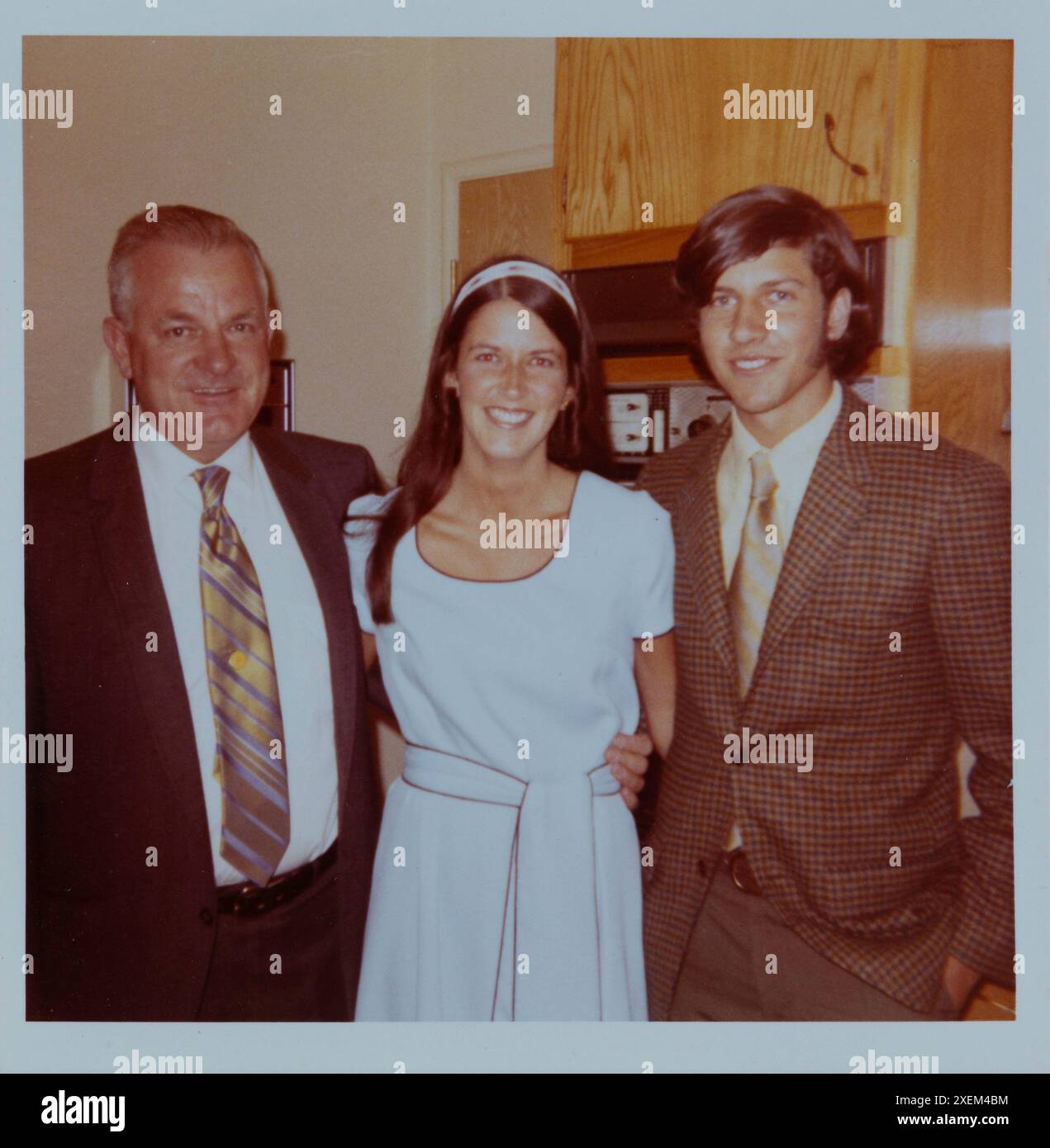 Young adult brother and sister pose with their father in their suburban ...