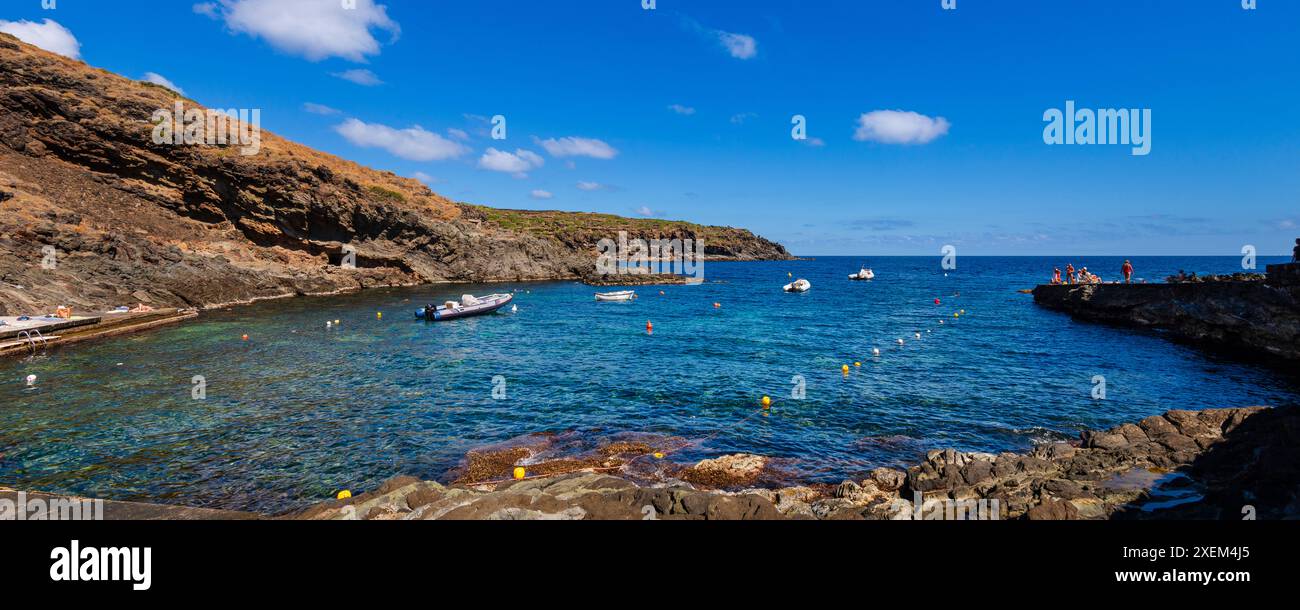 People enjoying the waterfront and small boats moored in the clear ...