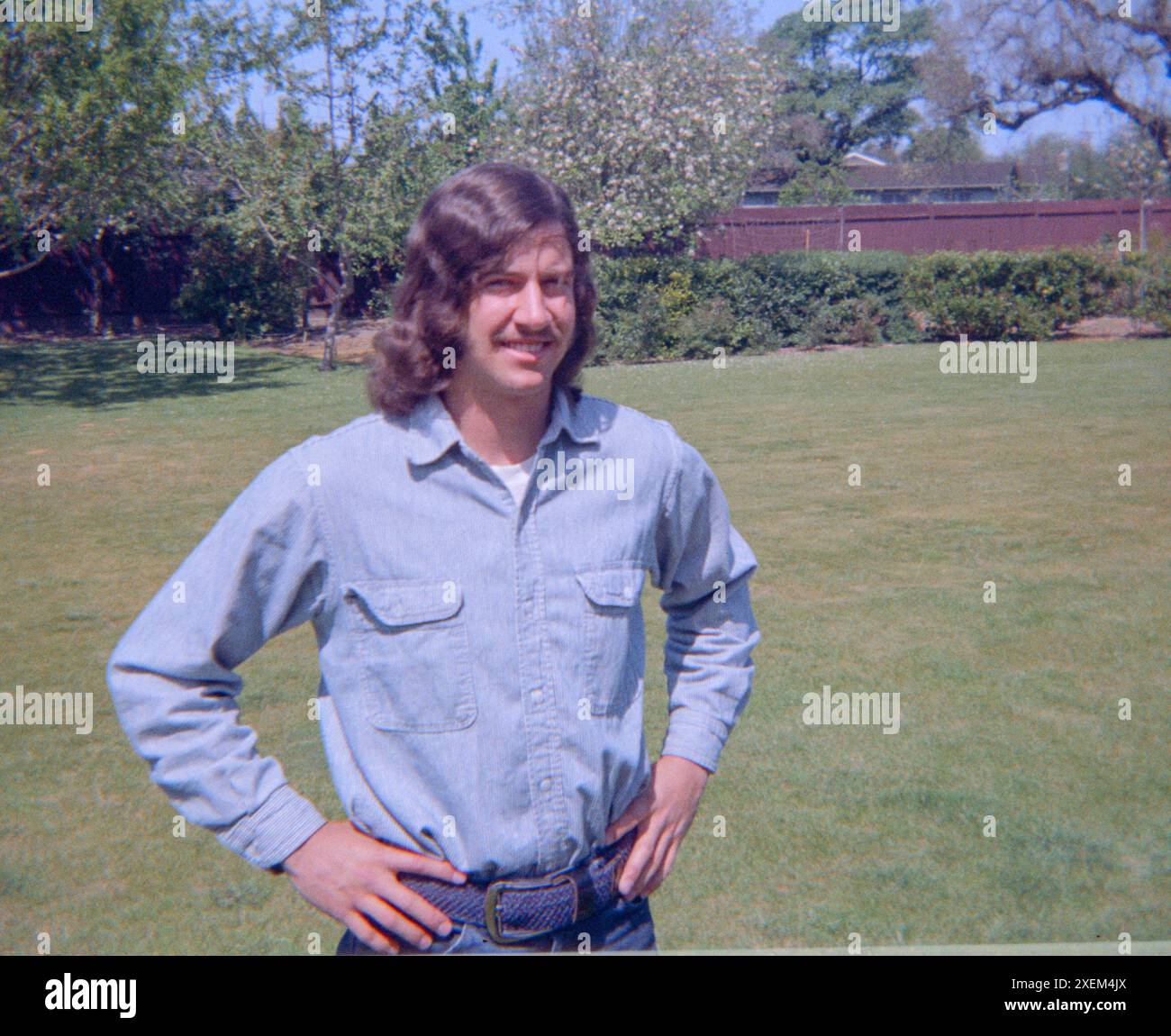 Confident, young man poses for camera in a suburban backyard, 1970s ...
