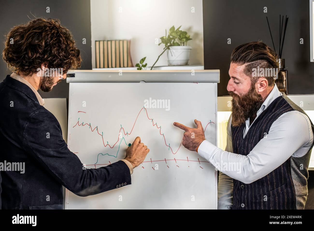 Businessmen analyzing financial chart on whiteboard. Two colleagues ...