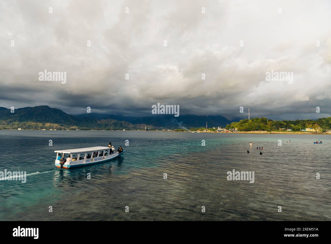 Boat and swimmers in the Flores Sea off Dutungan Island, Sulawesi ...