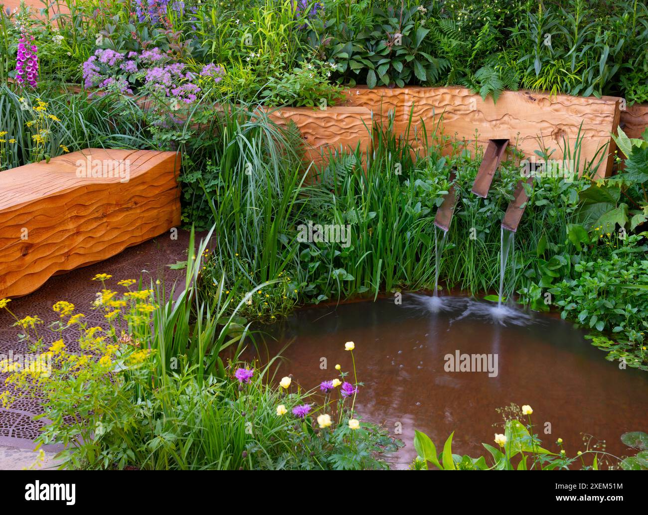 Water flowing into a pond through metal chutes and carved oak benches ...