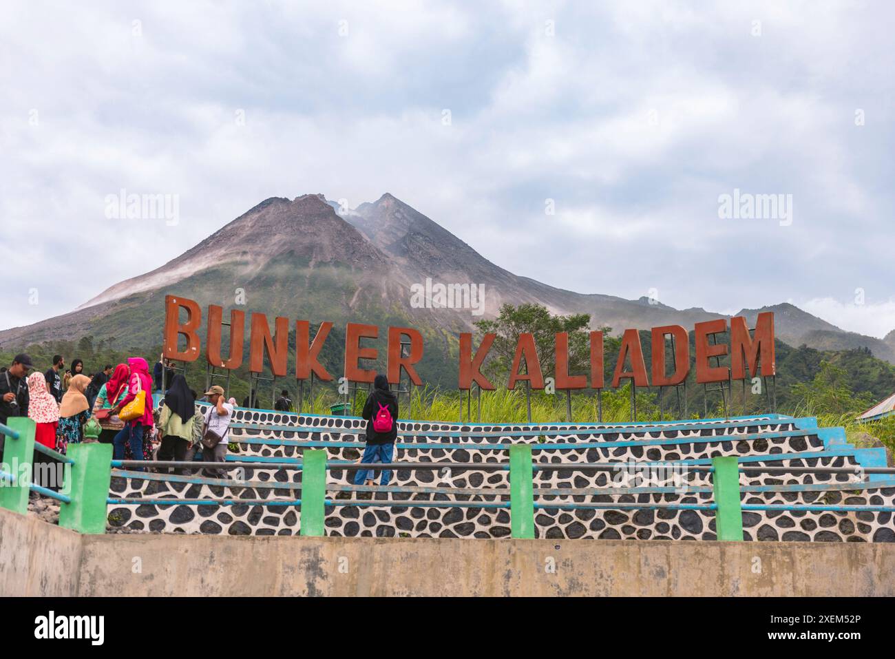 Tourists stand inside an abandoned concrete bunker viewing Mount Merapi ...