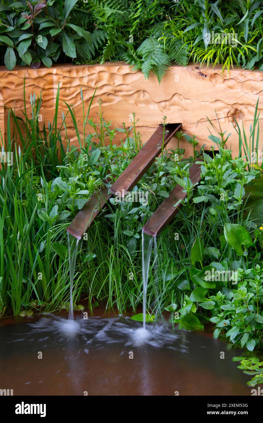Water flowing through metal chutes into a pond surrounded by ...