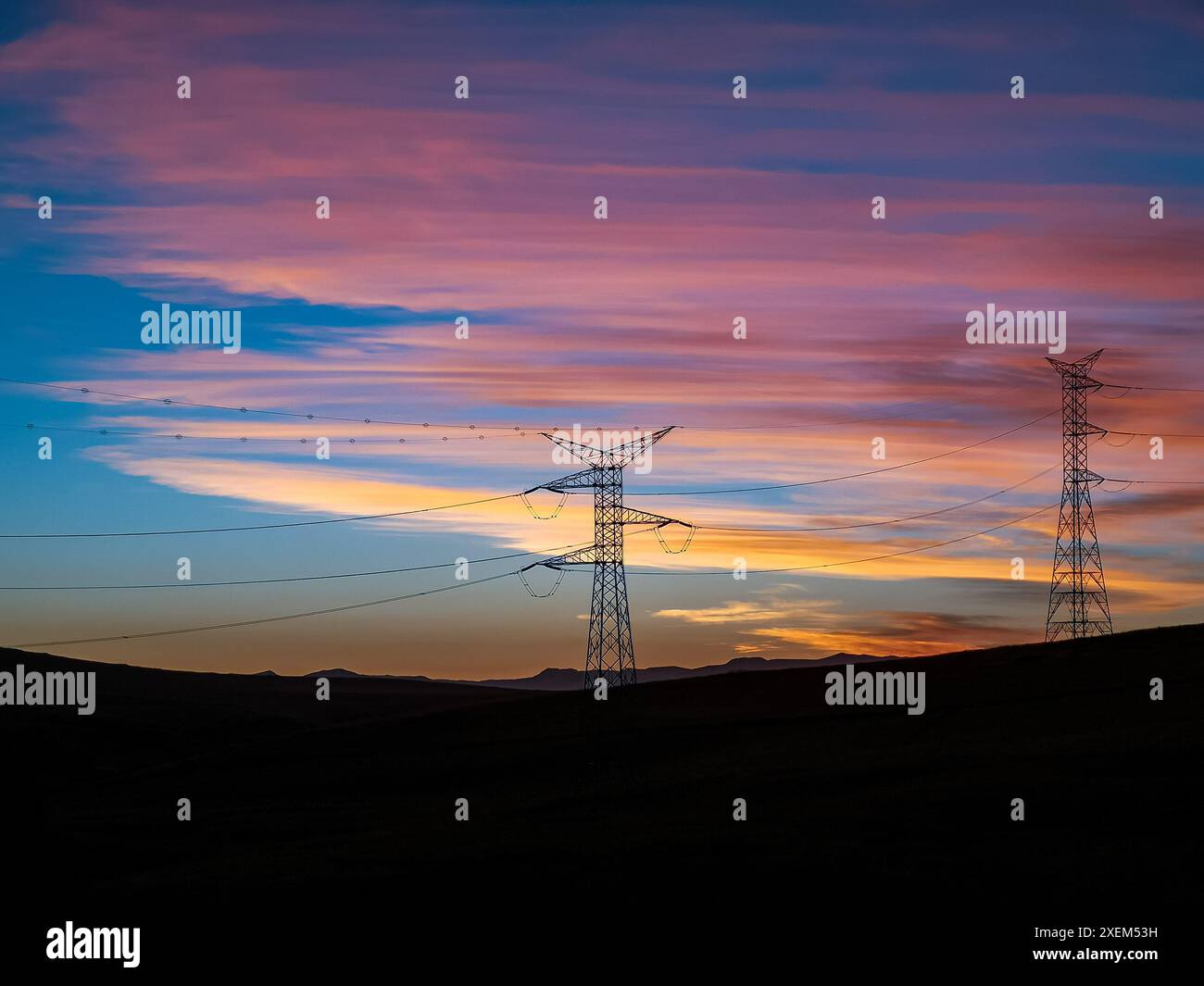 Electric pylons on a sunset with beautiful clouds Stock Photo - Alamy