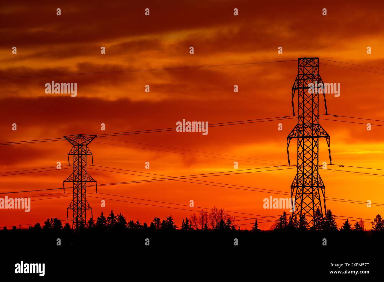 Silhouette of large metal electrical towers with a colourful dramatic ...