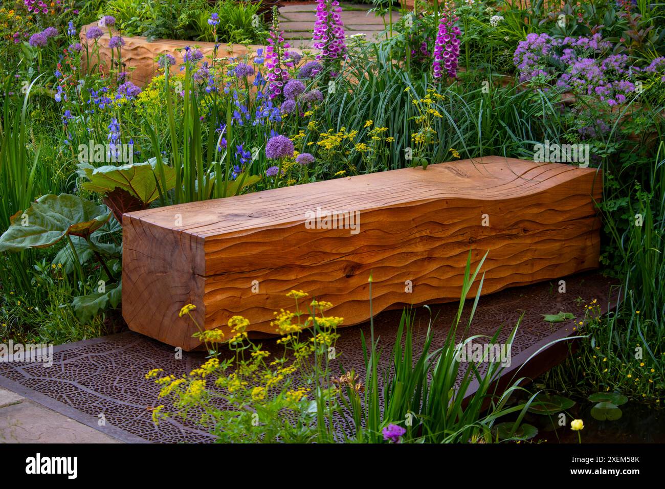 Carved oak benches surrounded by herbaceous planting including ...