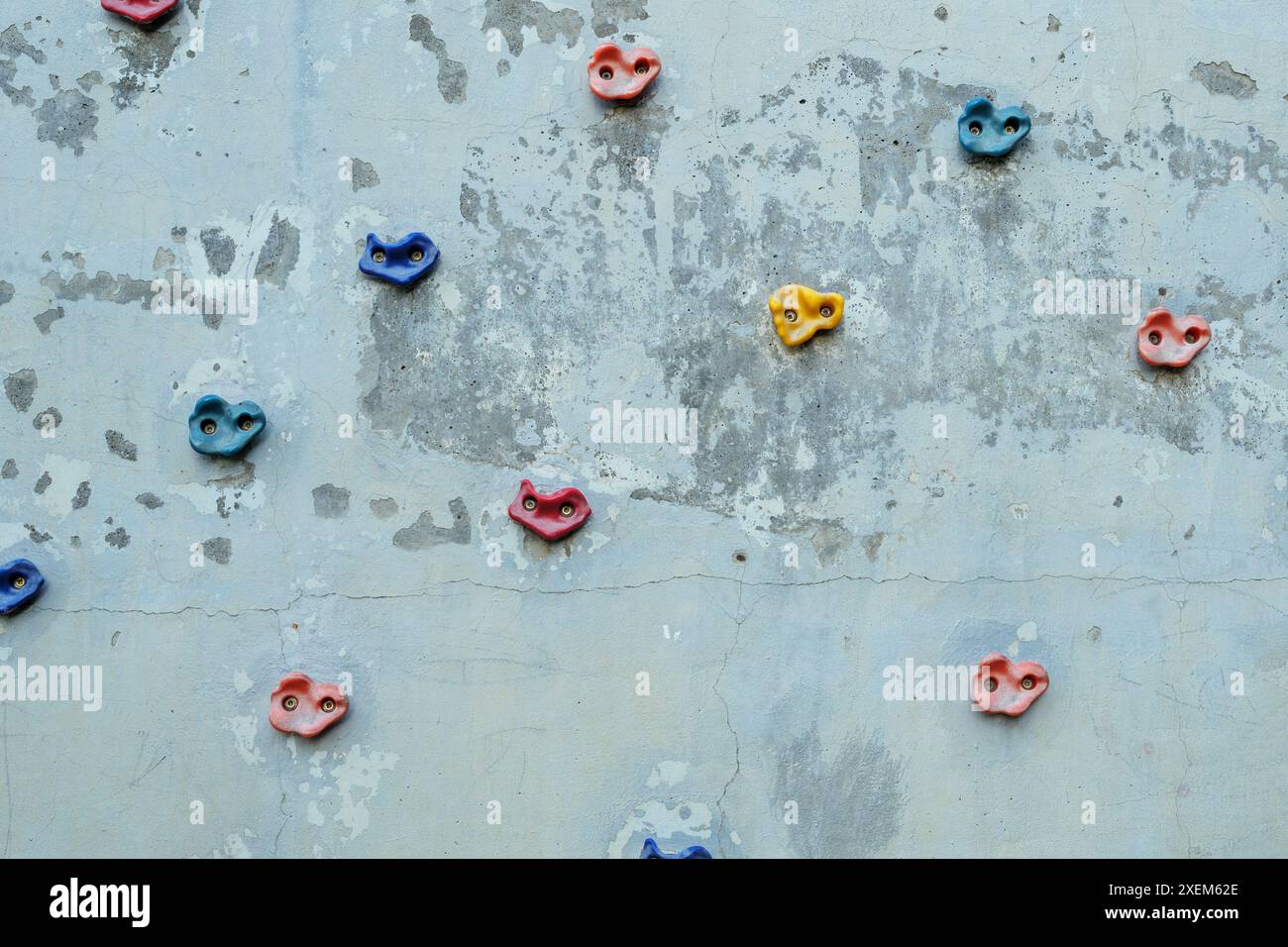 Front view of concrete climbing wall with various colored handholds ...