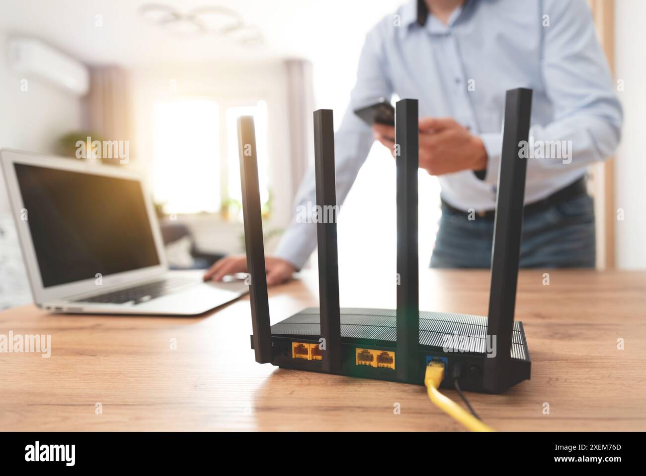 Modern wi-fi router on light table in room. Man using fast internet ...