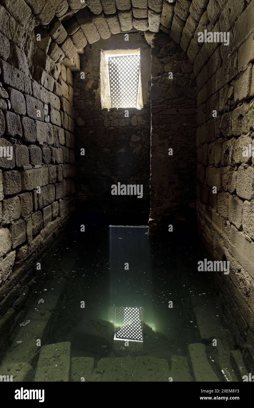 A dimly lit stone passageway leading to an ancient structure in Merida ...