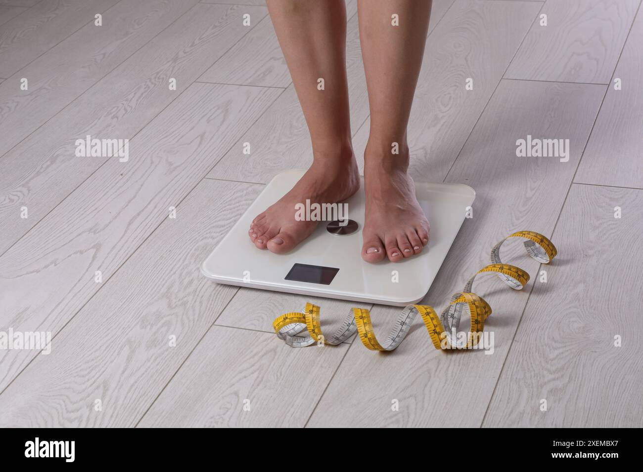 Eating disorder. Woman standing on floor scale and measuring tape ...