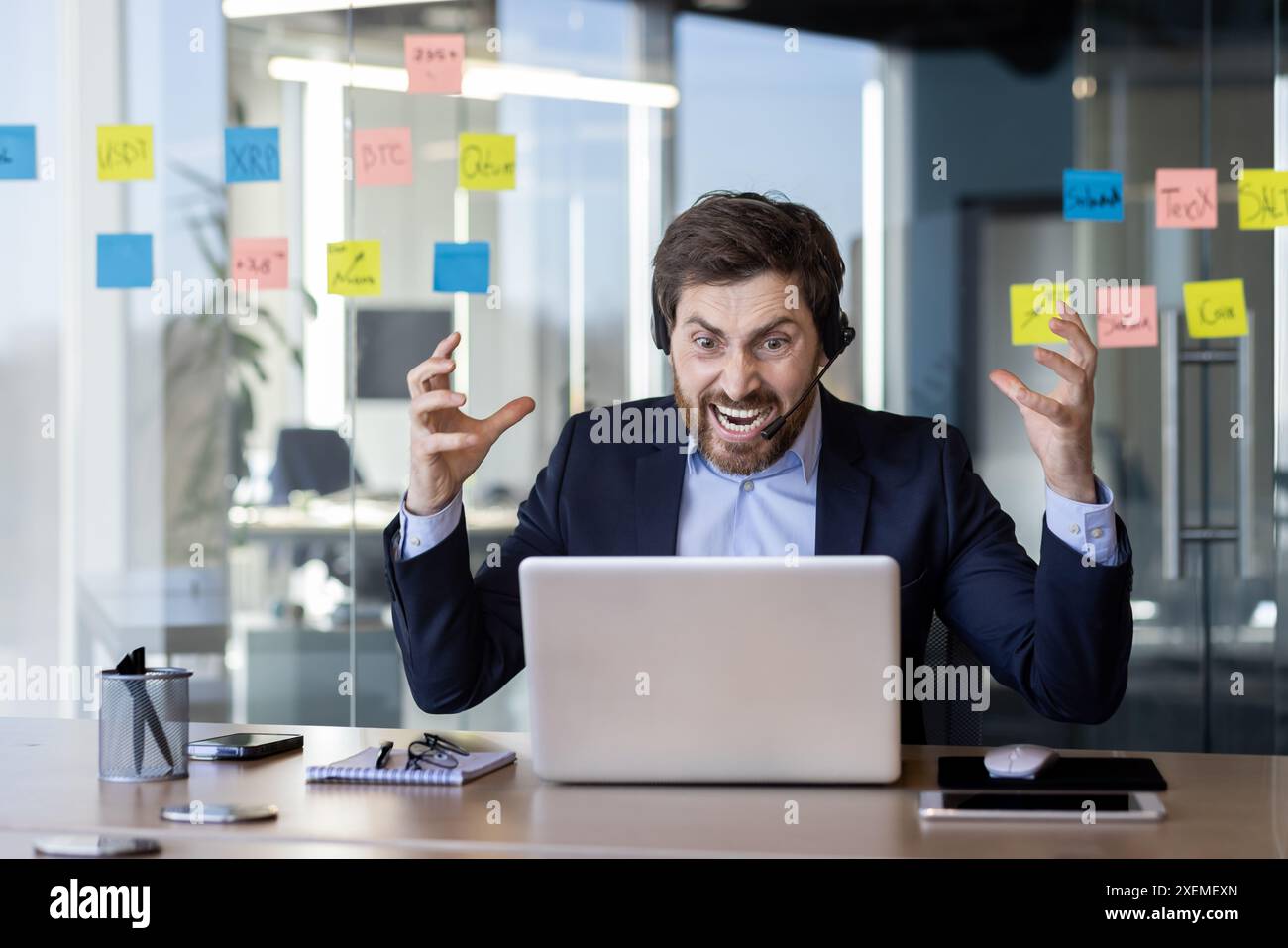 Frustrated businessman wearing headset showing anger while working on ...