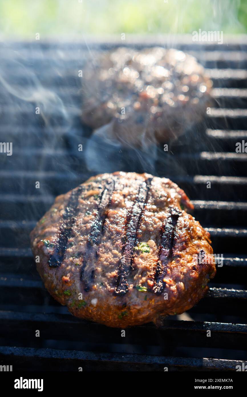 Grilled burger patty with smoke on hot grill close up. Cooking burgers ...