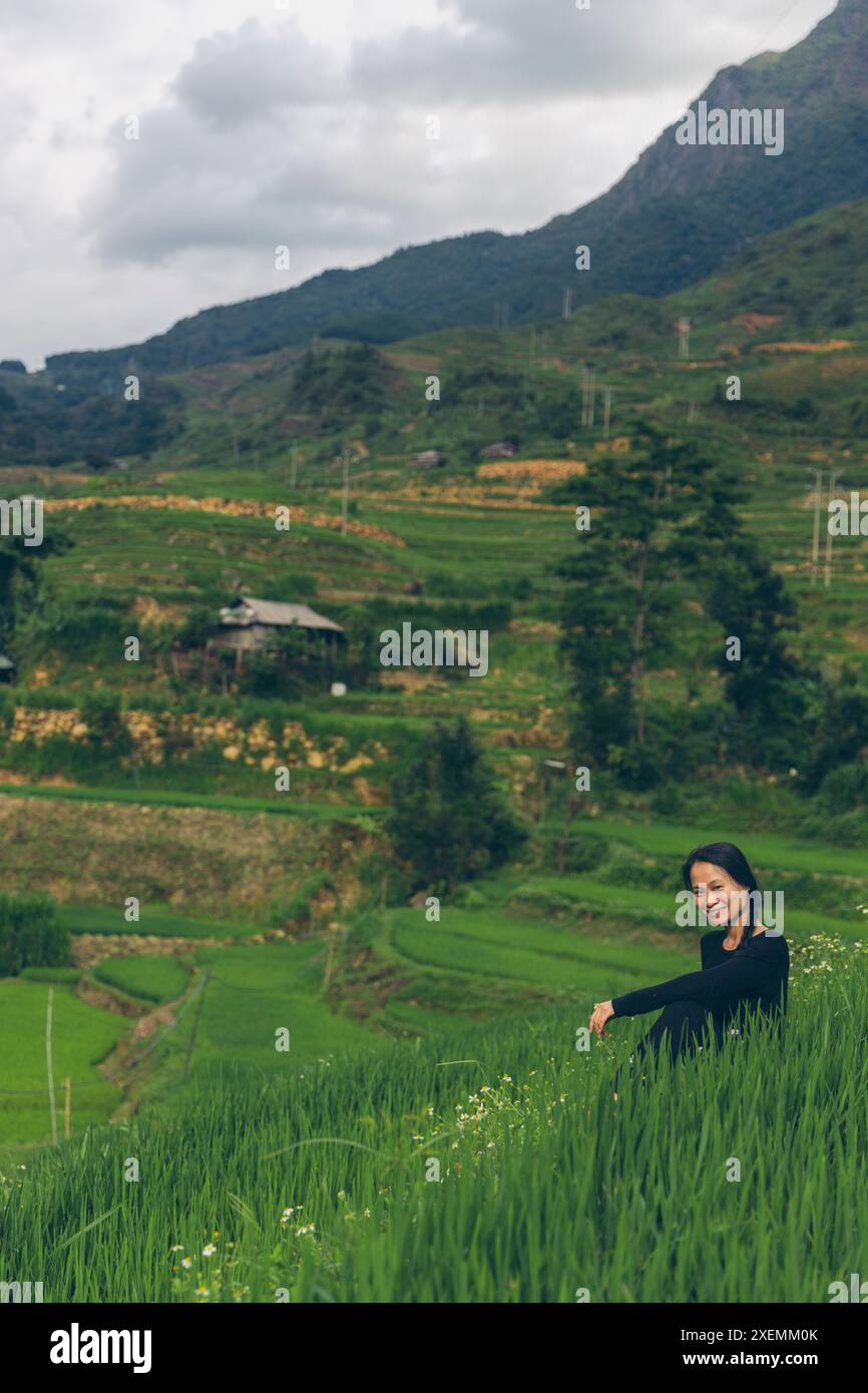 Young woman sitting on a hillside in a Vietnam farming community; Nam ...