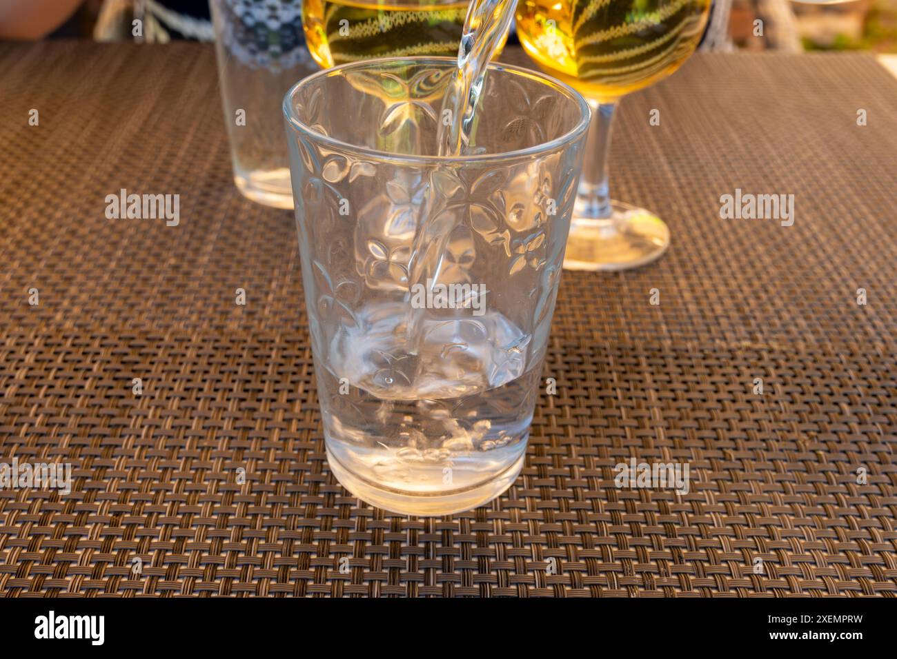 Waiter pouring mineral water from the glass bottle into a glass, food concept, close up Stock ...