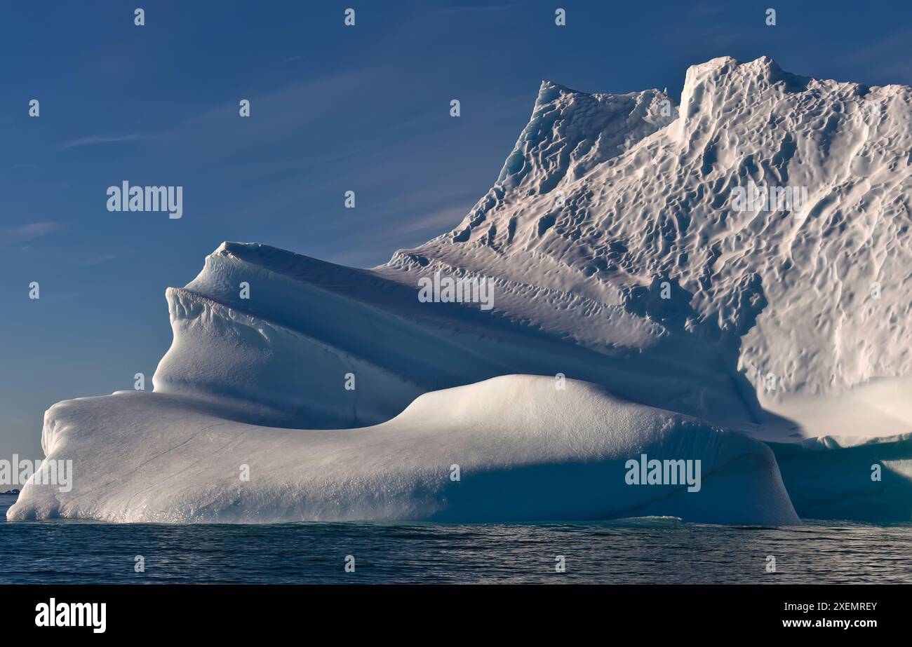 Iceberg with rugged formation in tranquil water with blue sky, near ...