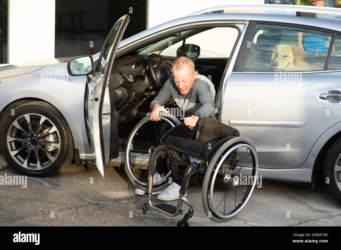 Paraplegic man assembles his manual wheelchair from the front seat of ...