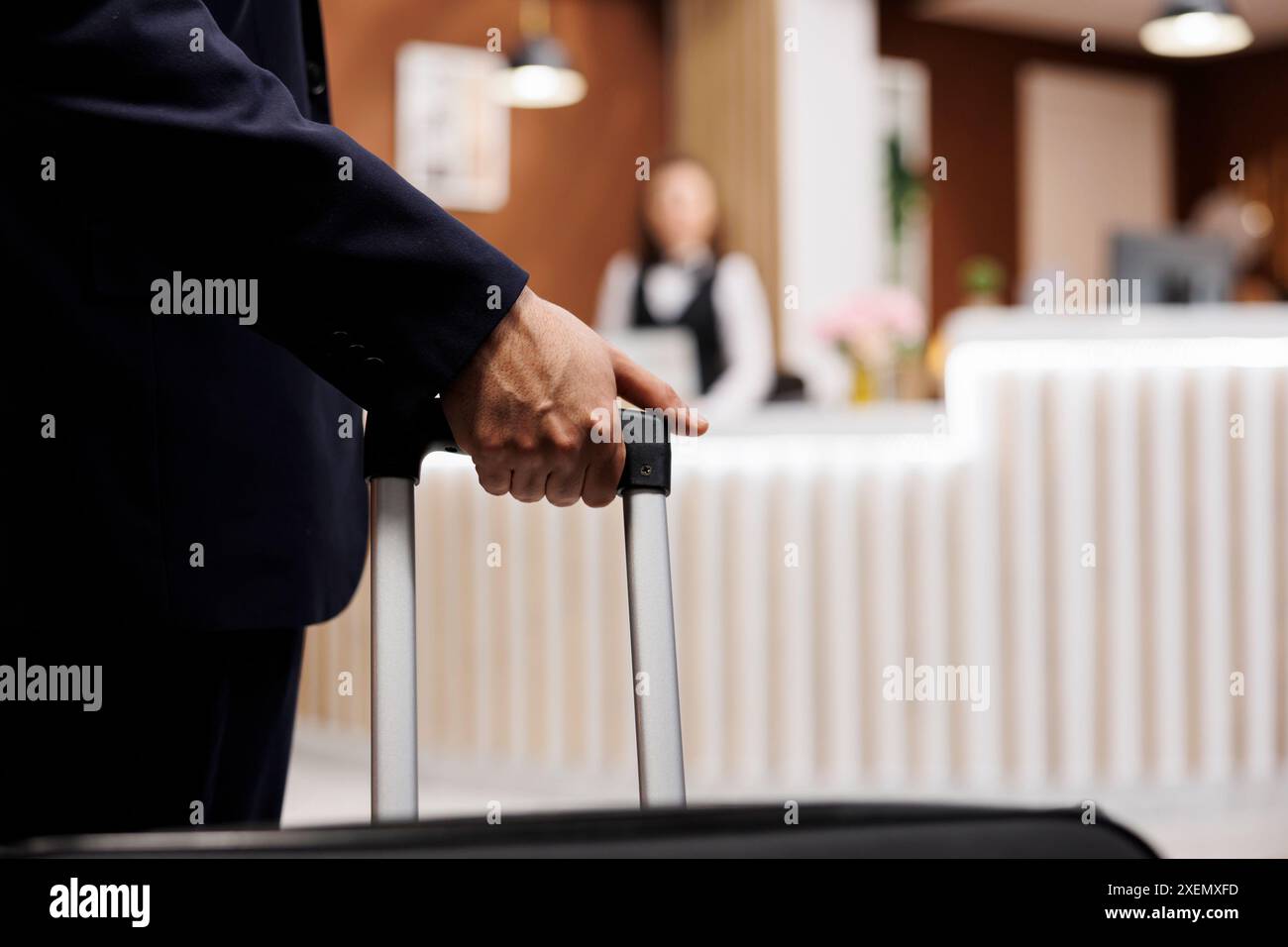 Businessman arriving in hotel lobby with suitcase, travelling for work ...