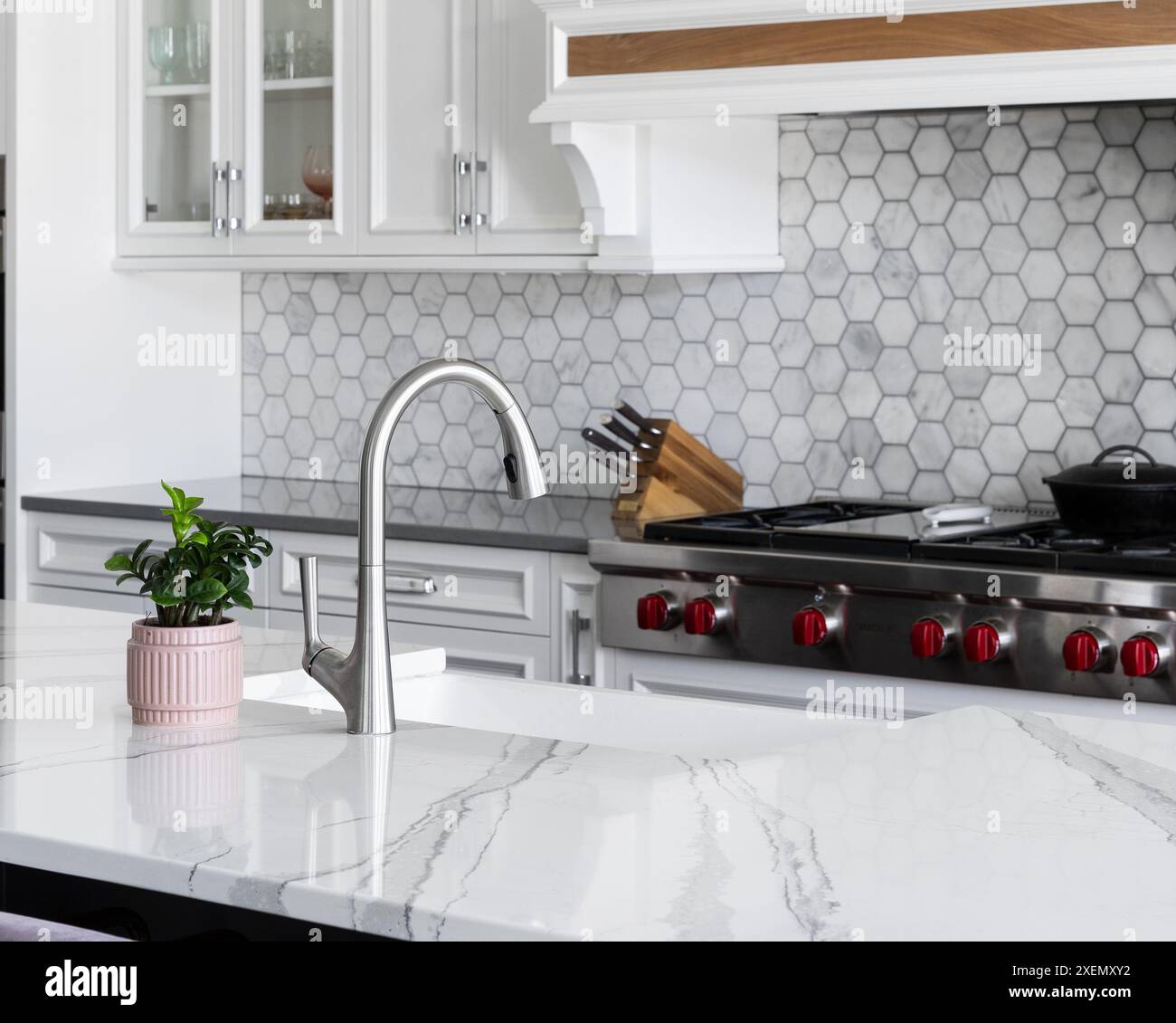 A kitchen sink detail, stainless faucet on a white farmhouse sink and ...