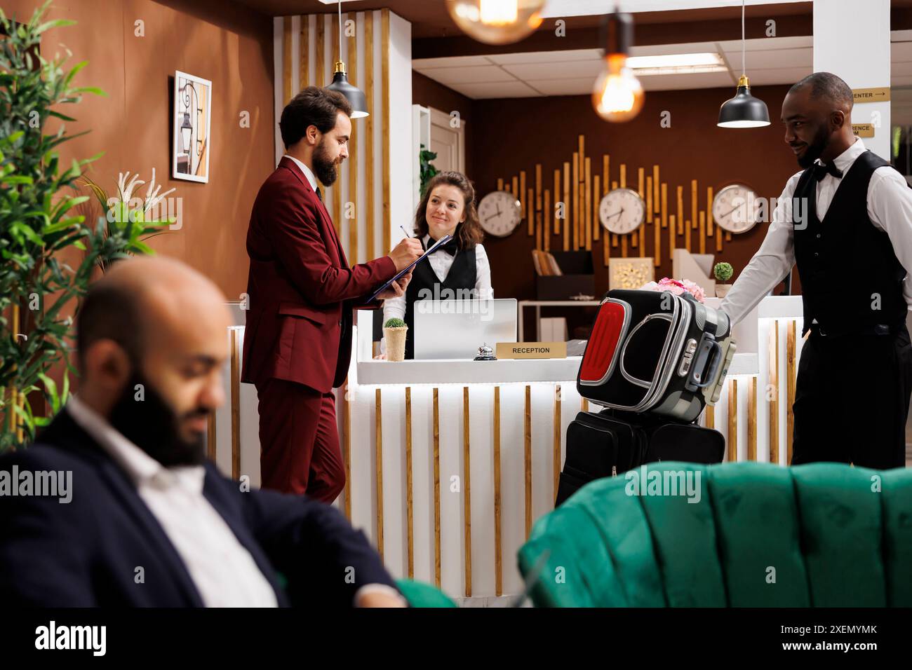 Traveller writing check in papers at reception counter, hotel staff ...