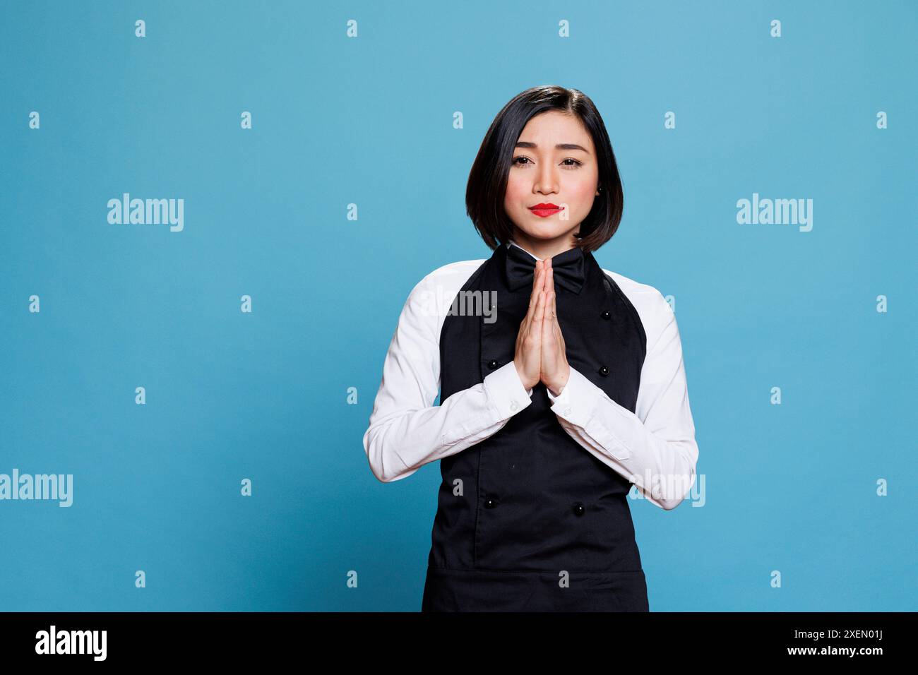 Asian waitress dressed in restaurant uniform standing in meditation ...