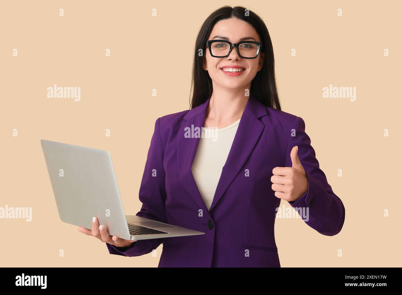 Female programmer with laptop showing thumb-up on beige background ...