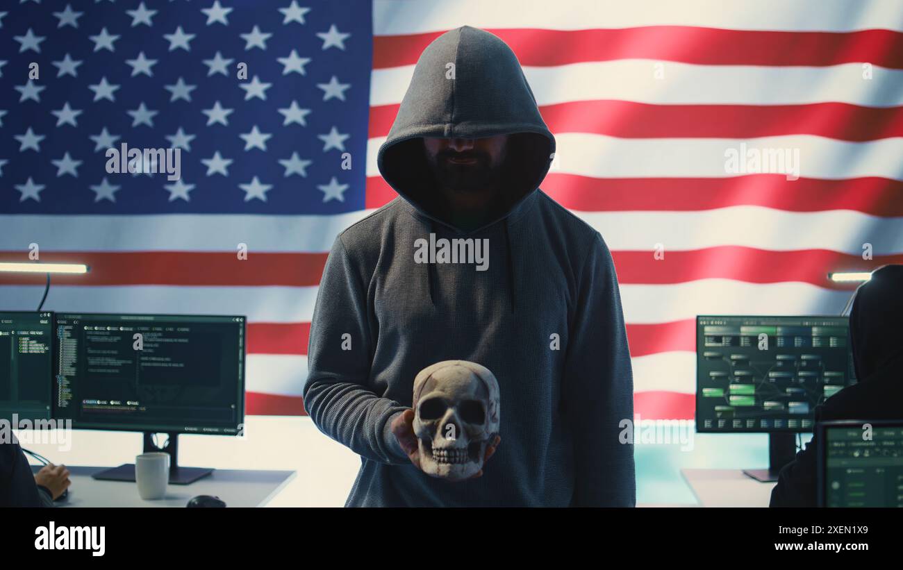 American man in a dark hood making death threats with human skull ...