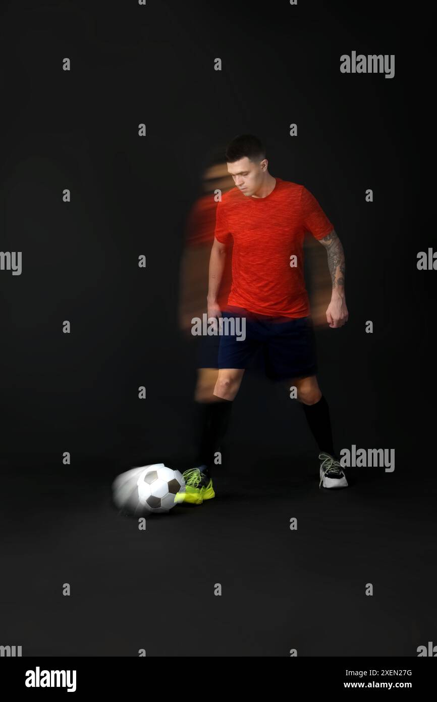 Male footballer playing with ball in motion on black background Stock ...