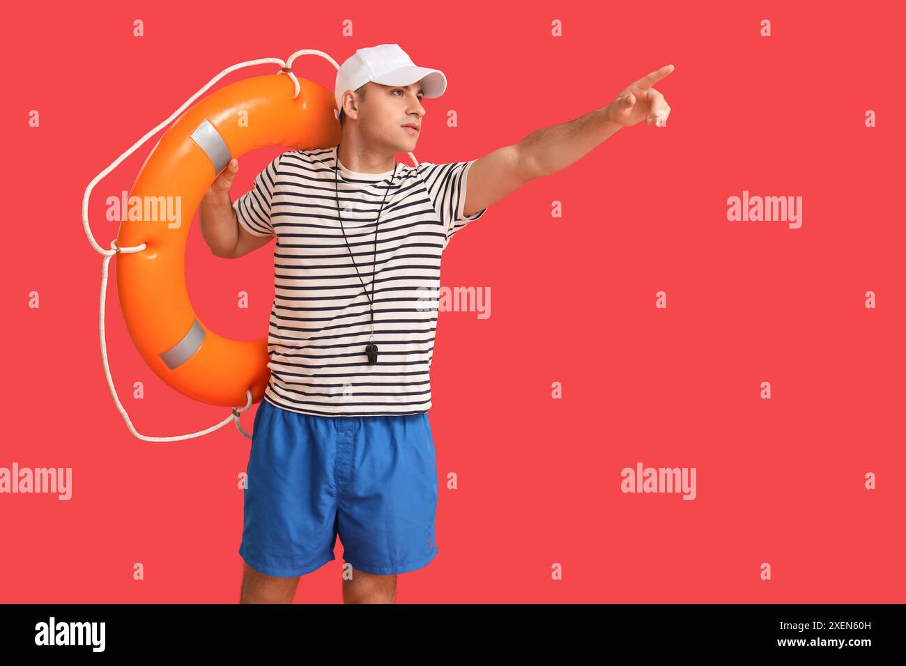 Handsome male lifeguard with ring buoy pointing at something on red ...