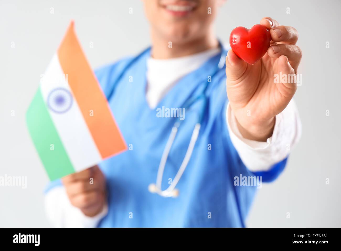 Male doctor with flag of India and heart on grey background, closeup ...