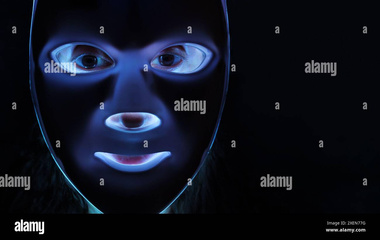 A close-up shot of a woman wearing a light therapy mask on a black ...